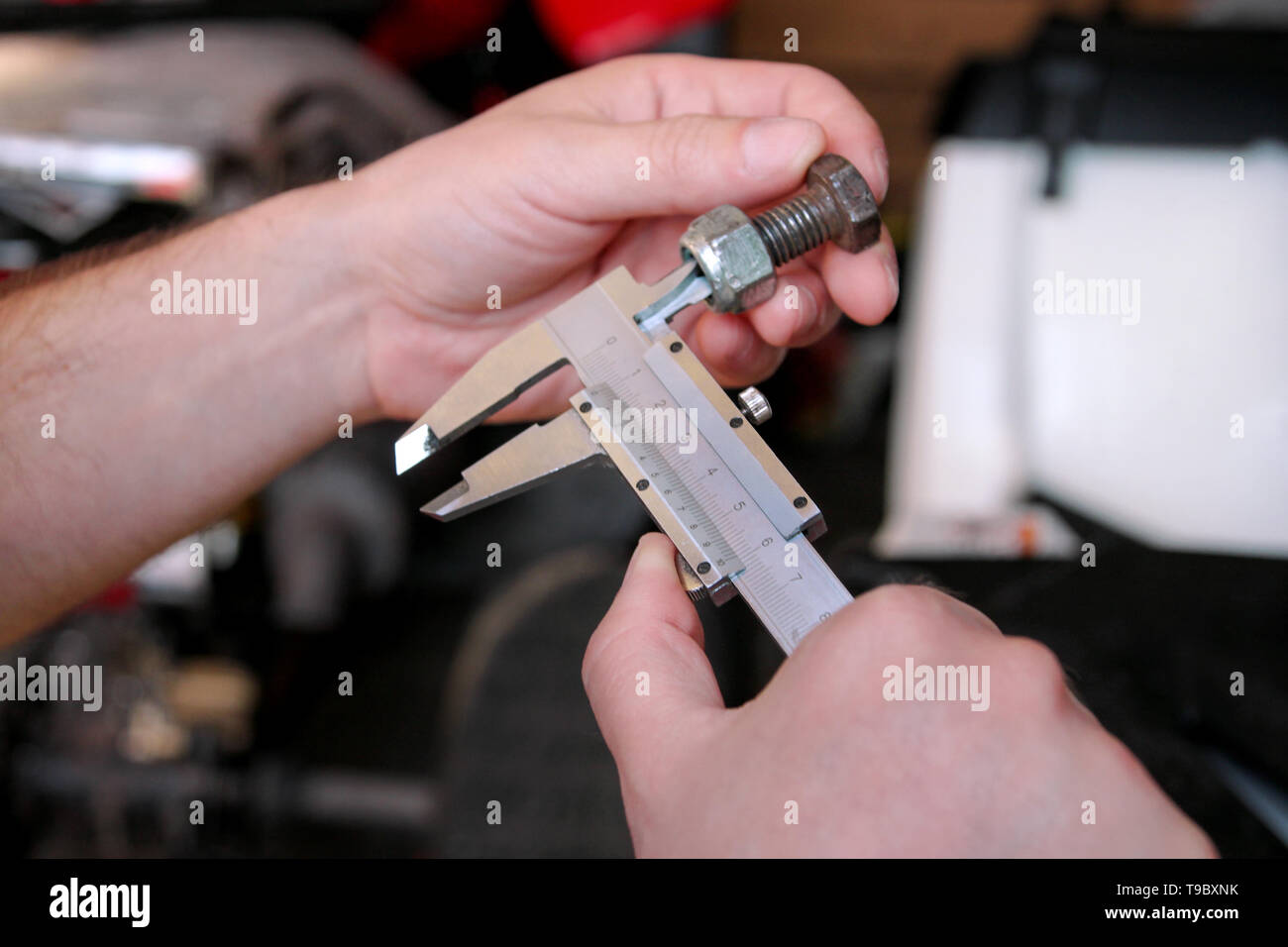 Worker with tools in hands. Mechanic is checking and measuring screw ...