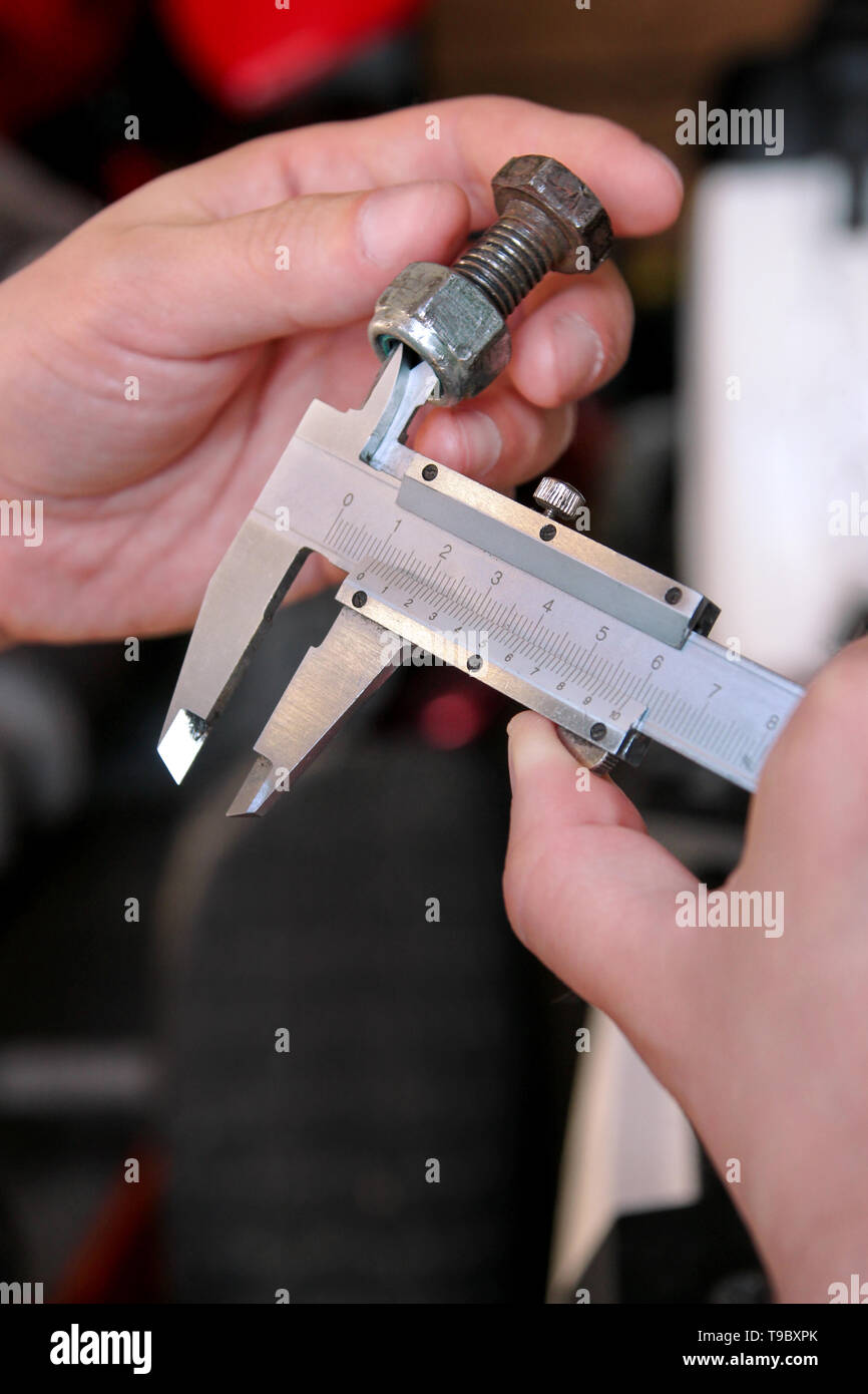 Worker with tools in hands. Mechanic is checking and measuring screw ...