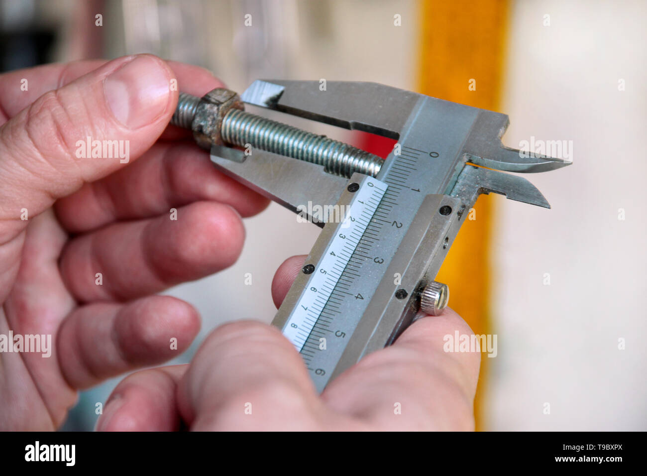 Worker with tools in hands. Mechanic is checking and measuring screw ...
