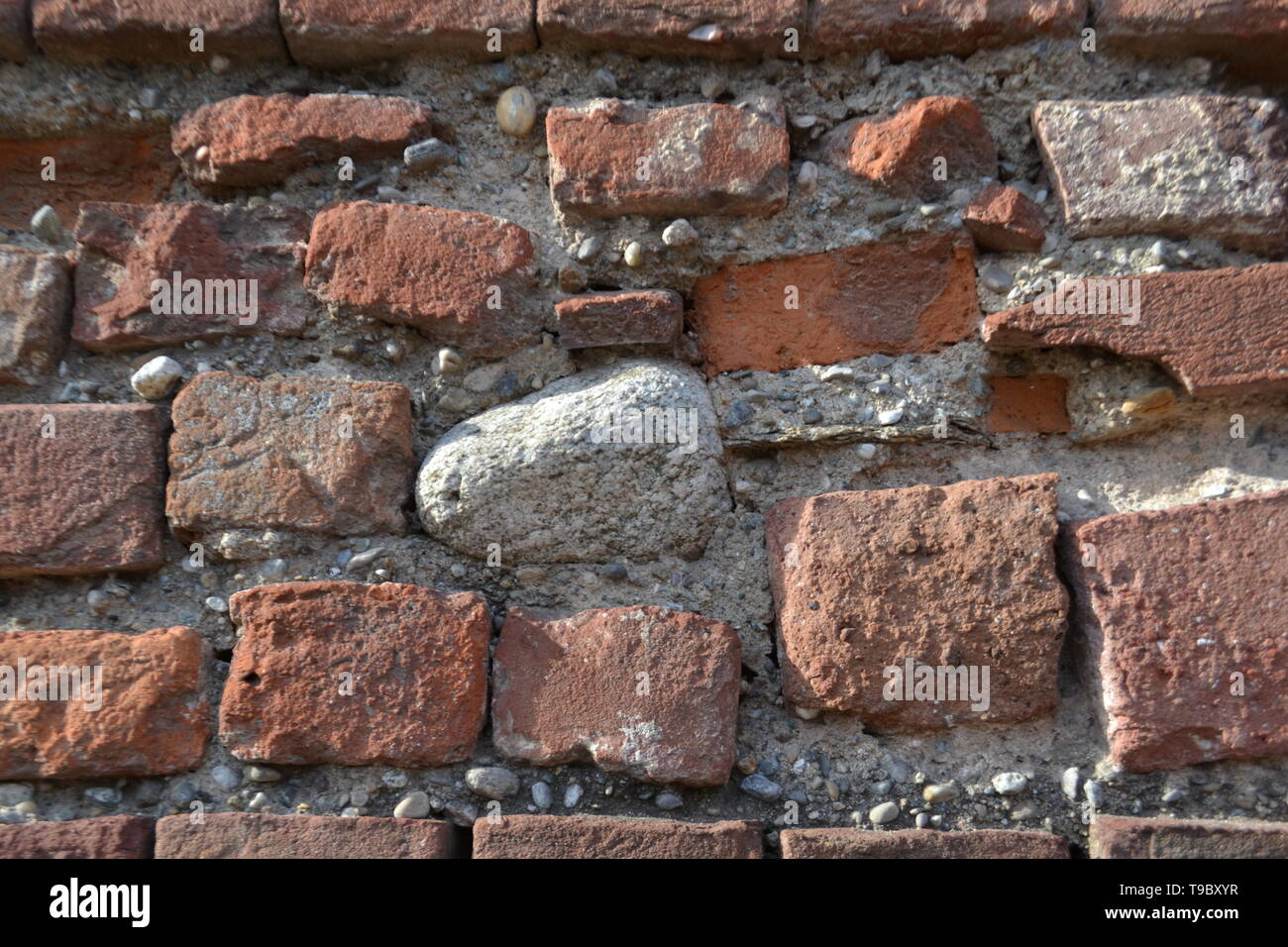 Close-up view to an ancient medieval wall made of red bricks and grey ...