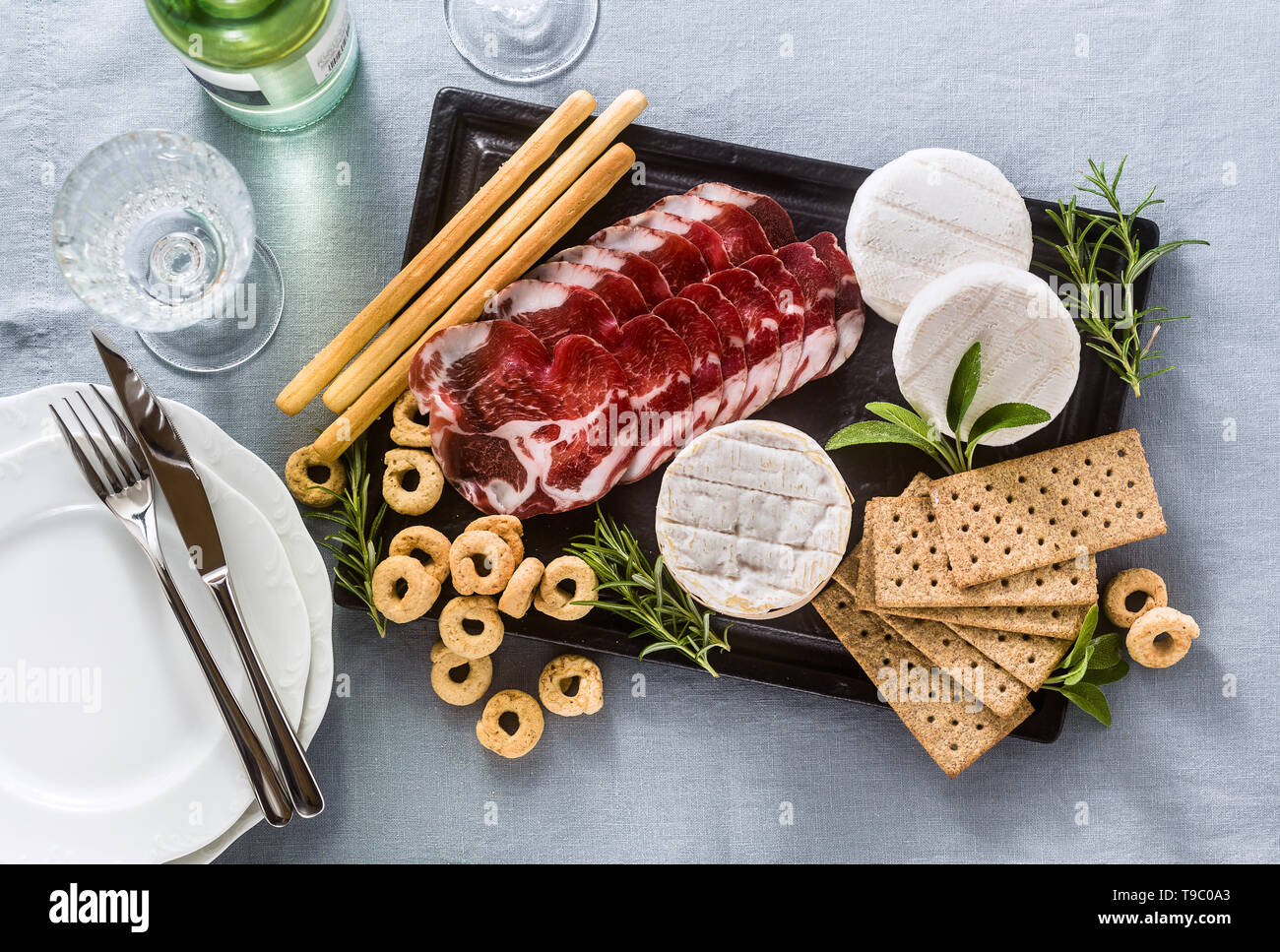 cold cuts and cheese are served on a tray on a table with white wine ...