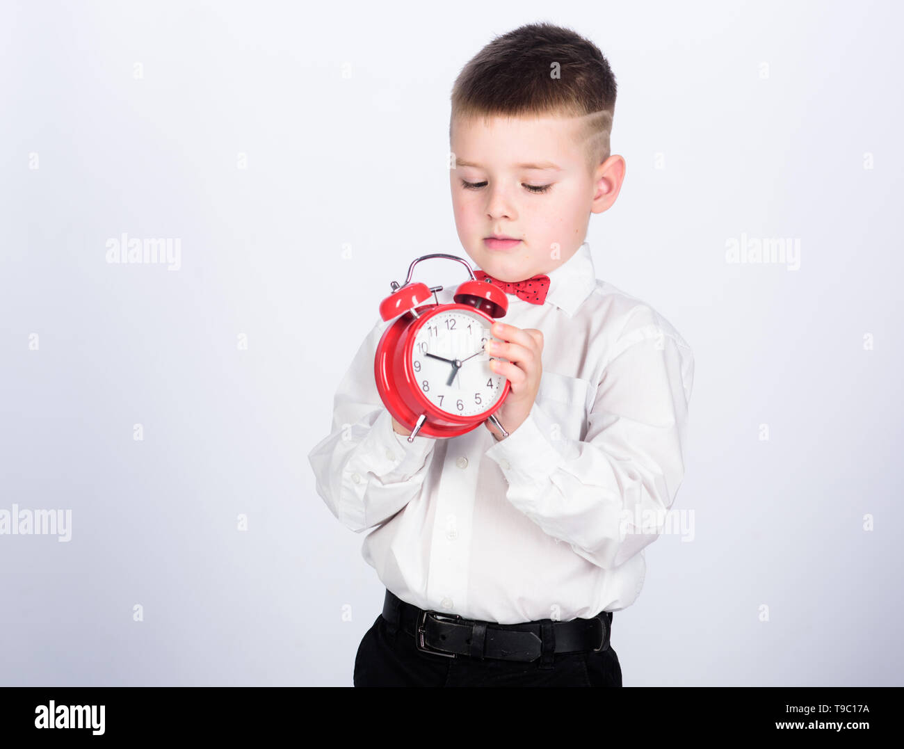 Set up alarm clock. Child little boy hold red clock. It is time ...