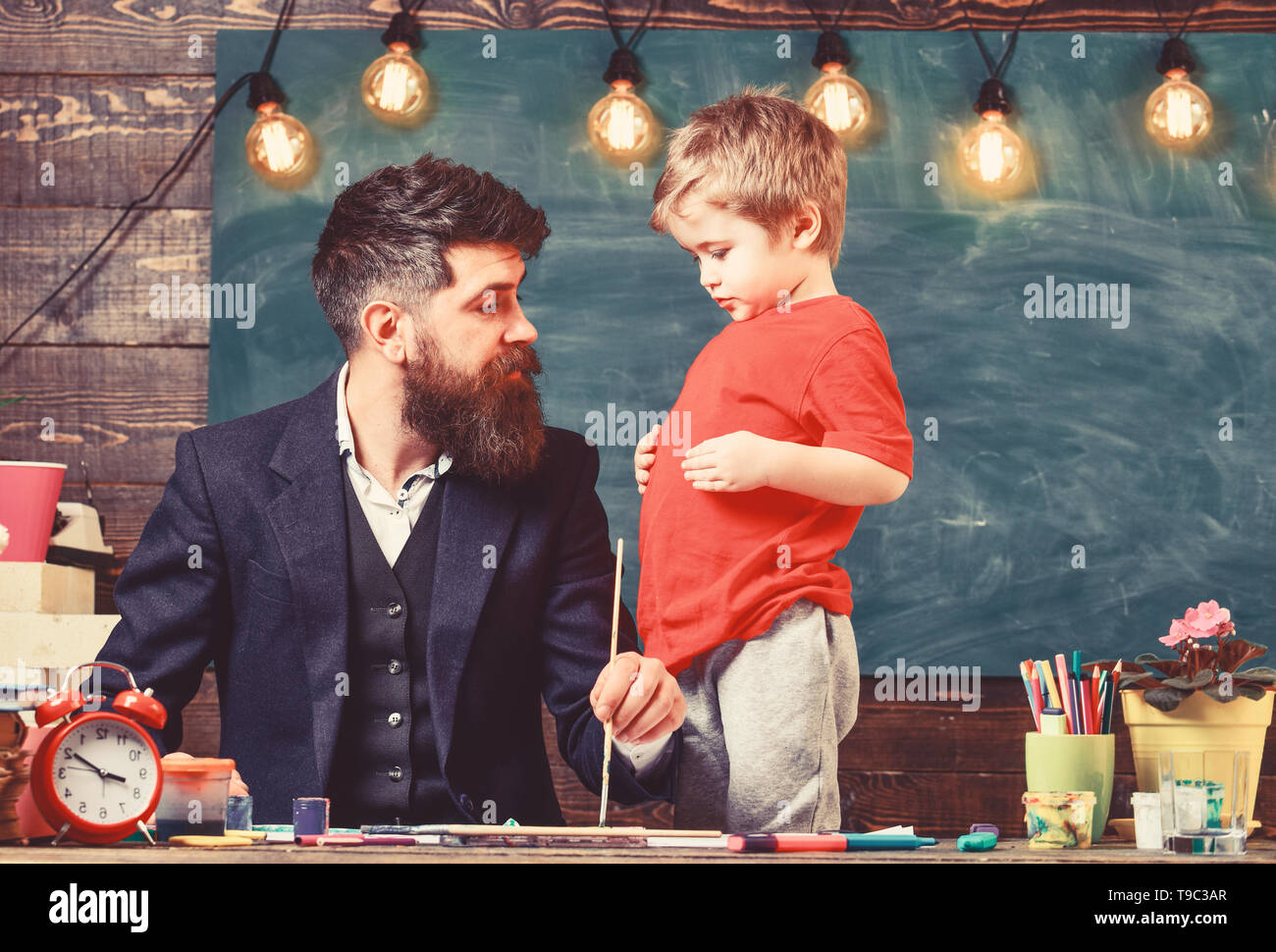 Fatherhood concept. Teacher with beard, father teaches little son to ...