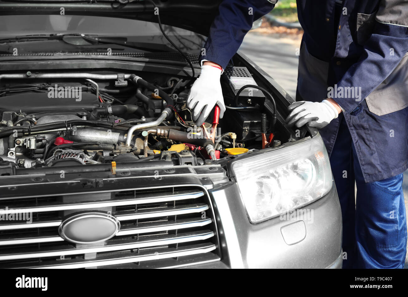 Male mechanic charging a car battery Stock Photo - Alamy