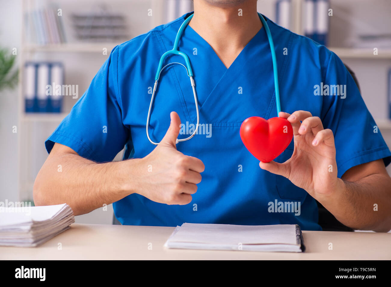 Male doctor cardiologist holding heart model Stock Photo - Alamy