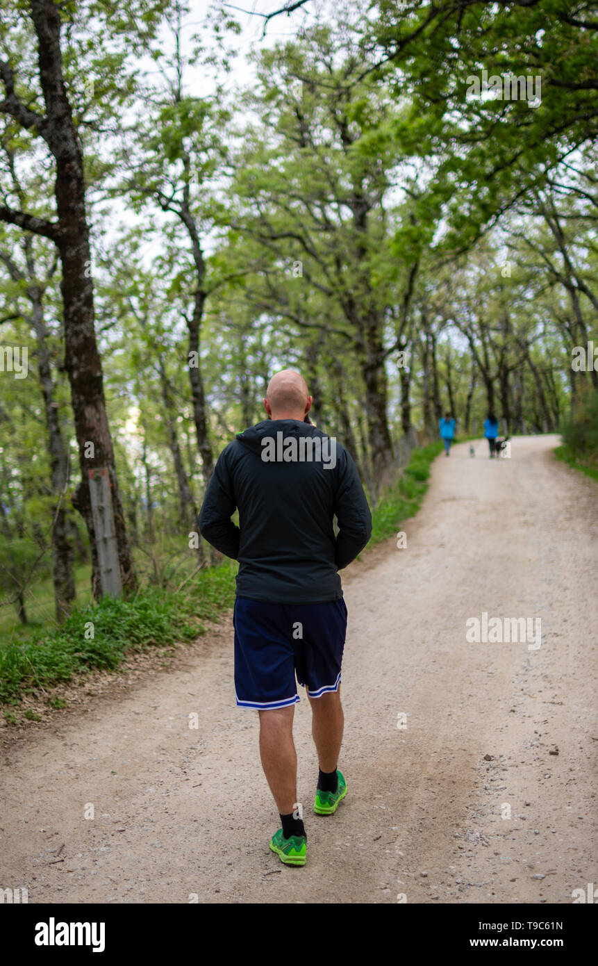 Young man seen from back with a hoodie sweatshirt walking quietly on a ...