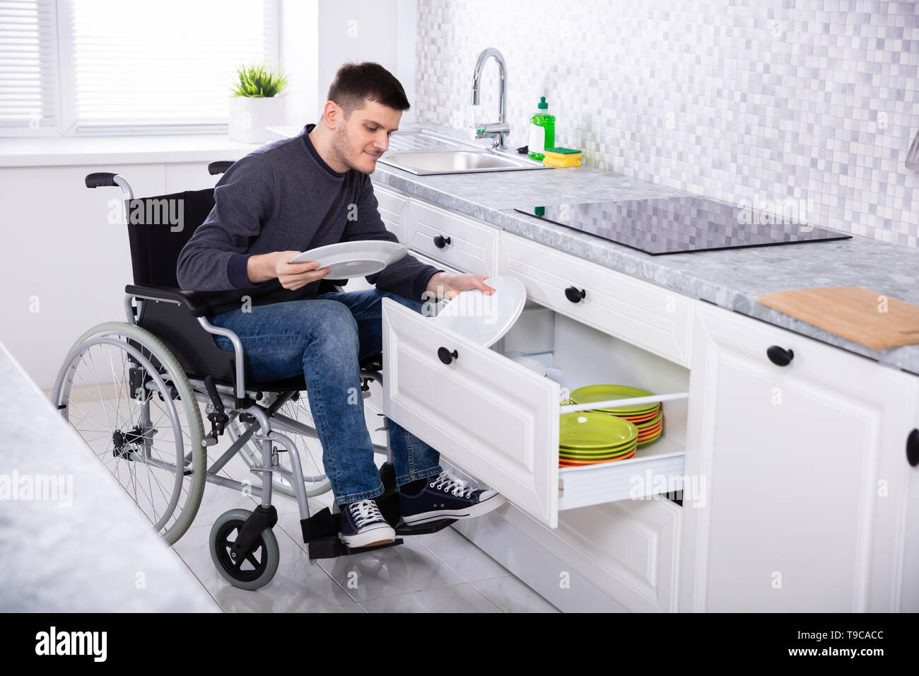 Young Happy Disabled Man Sitting On Wheelchair Arranging Plates In ...