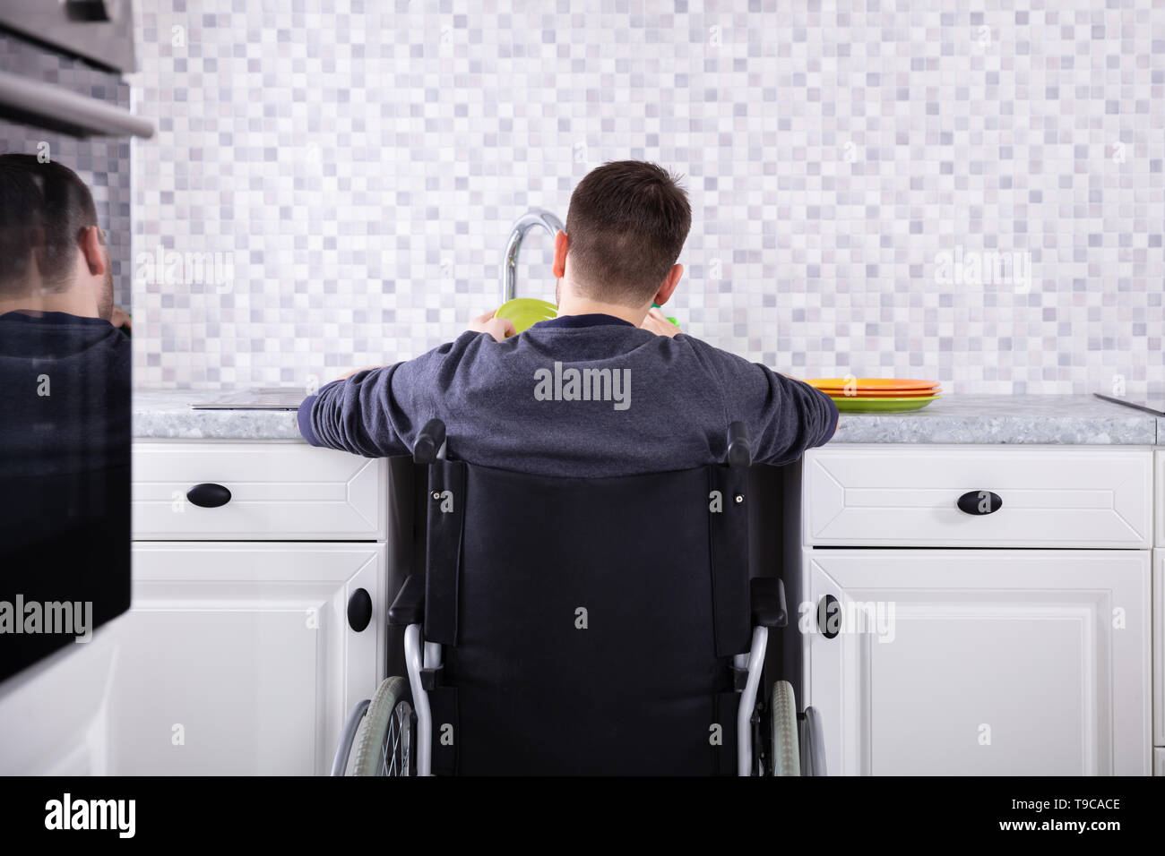 Handicapped Man Sitting On Wheelchair Washing And Cleaning Dishes In ...