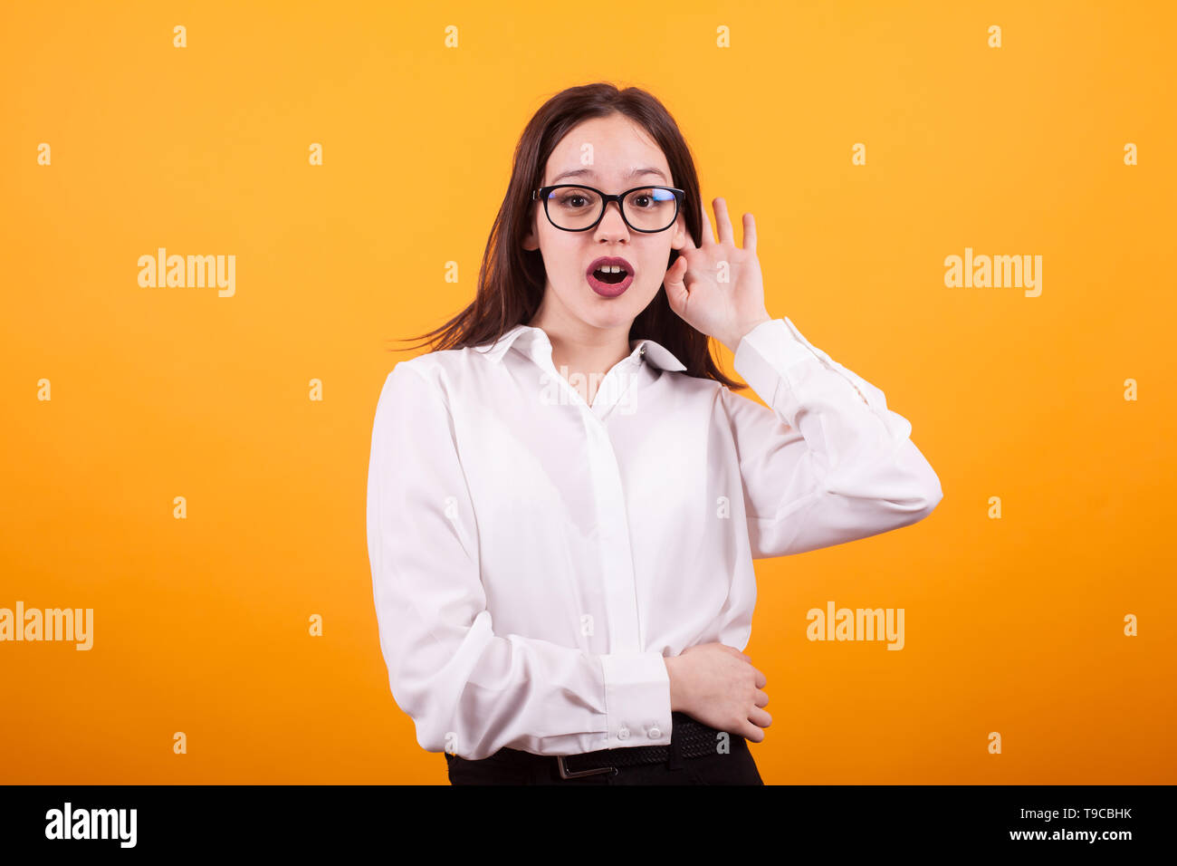 Portrait of pretty schoolgirl with wow expression in studio over yellow ...