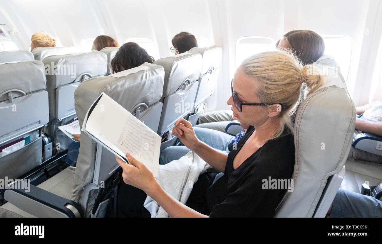 Woman reading magazine on airplane during flight. Female traveler ...