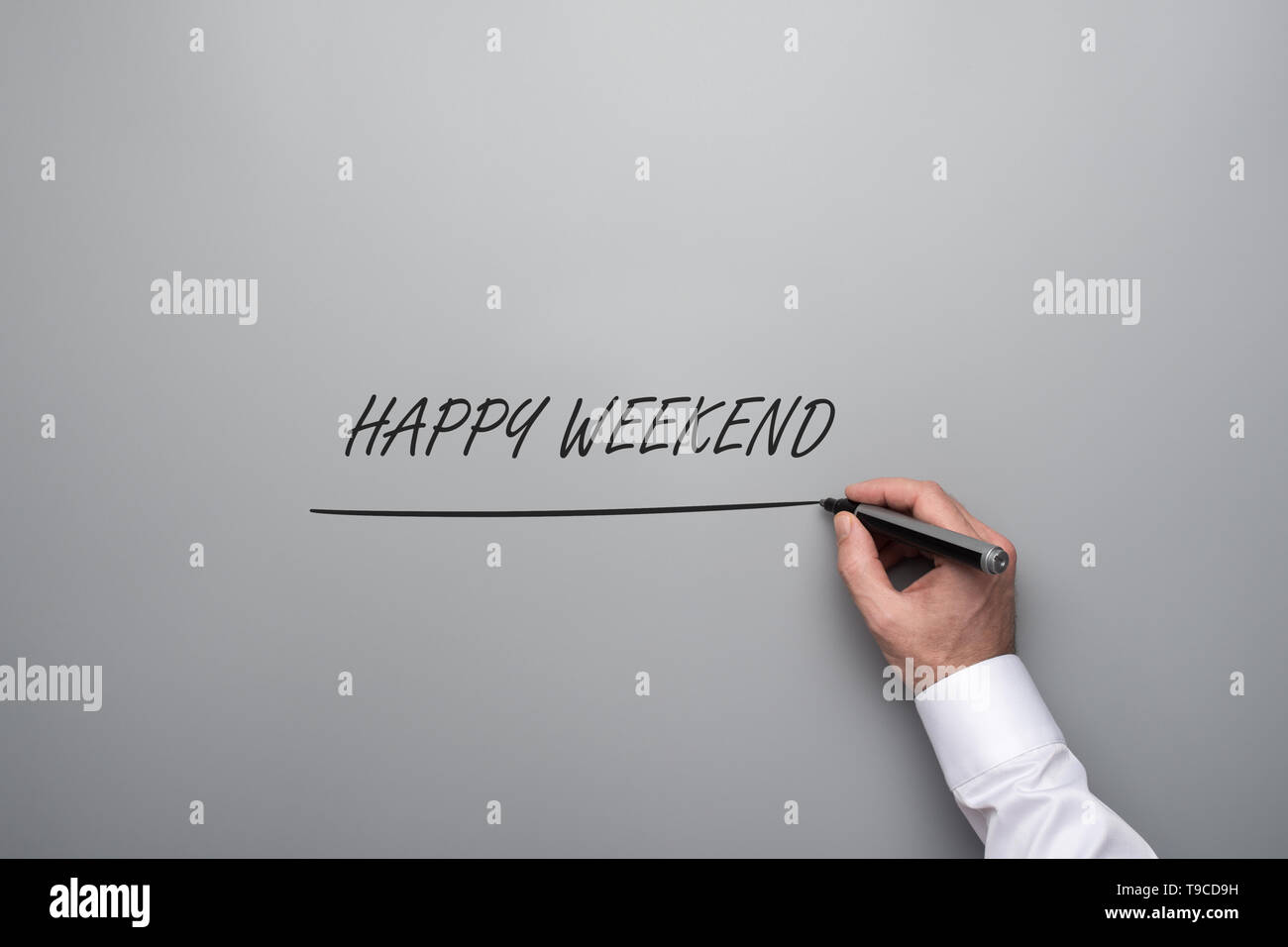 Male hand underlining a Happy weekend sign with black marker over grey ...