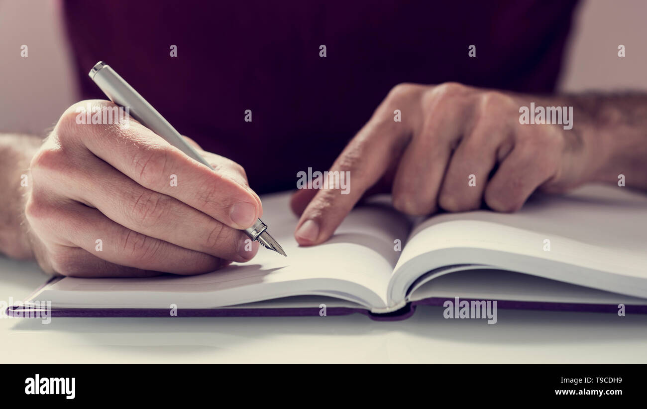 Front closeup view of male student writing notes with fountain pen in ...