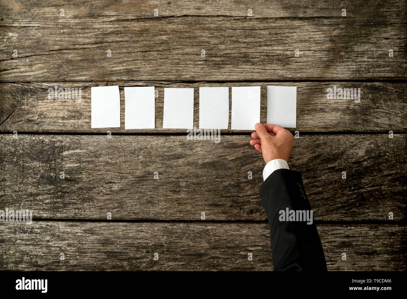 Top view of male hand placing six empty white cards in a row over a ...