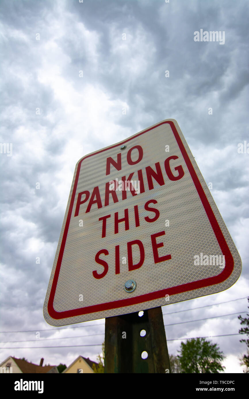 No Parking This Side sign with dark storm clouds in the background ...