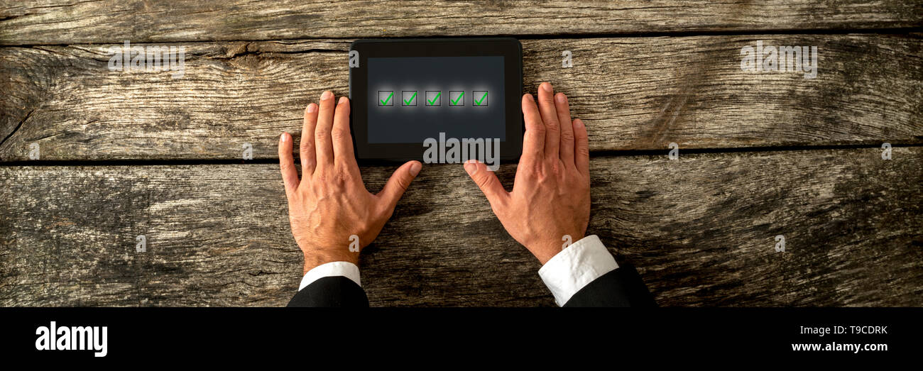 Overhead view of male hand holding a digital tablet with five check ...