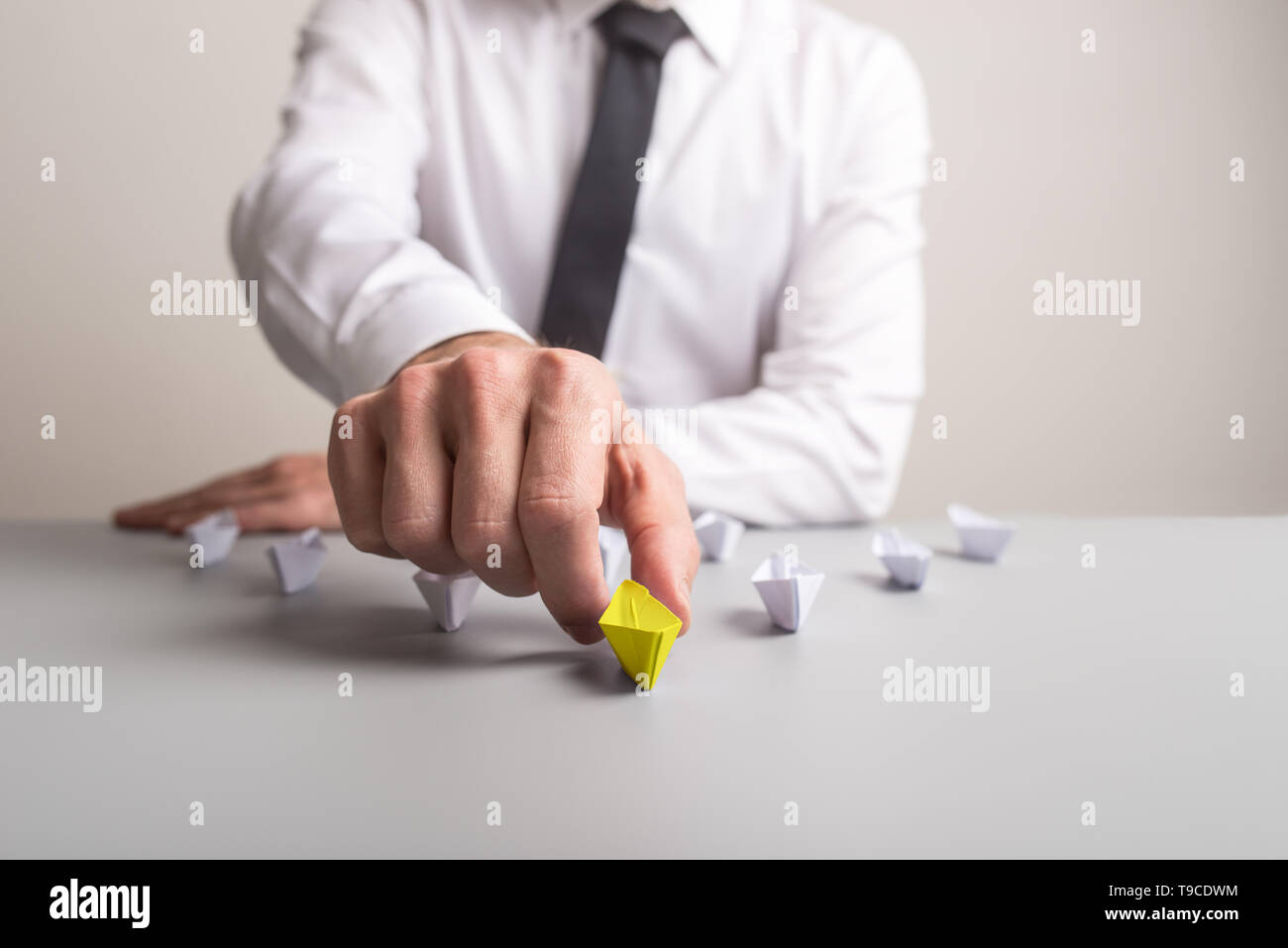 Business executive sitting at his desk pushing forward a yellow colored ...