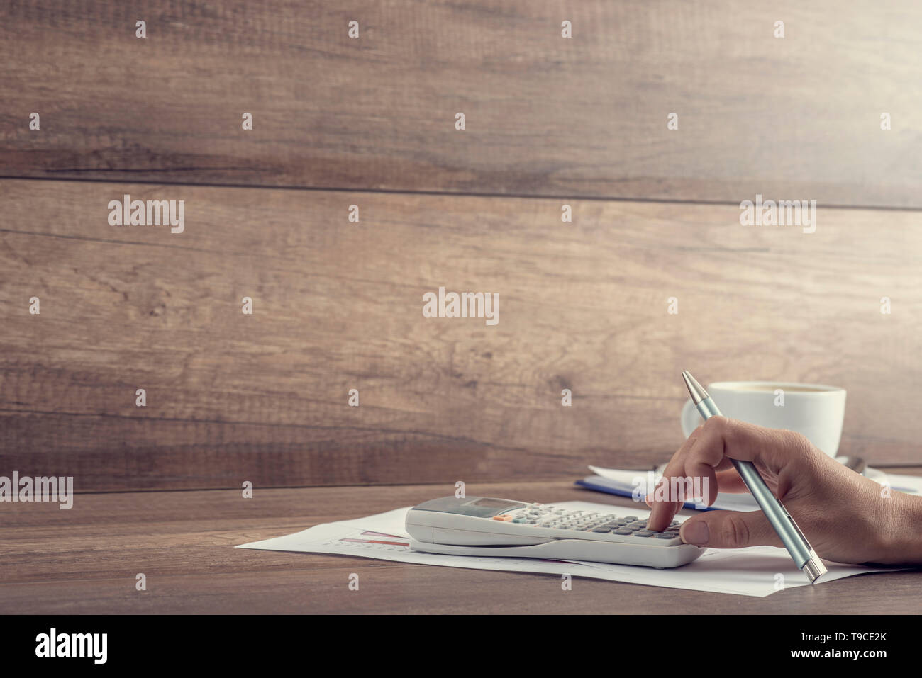 Side view of accountant balancing the books with calculator, toned ...