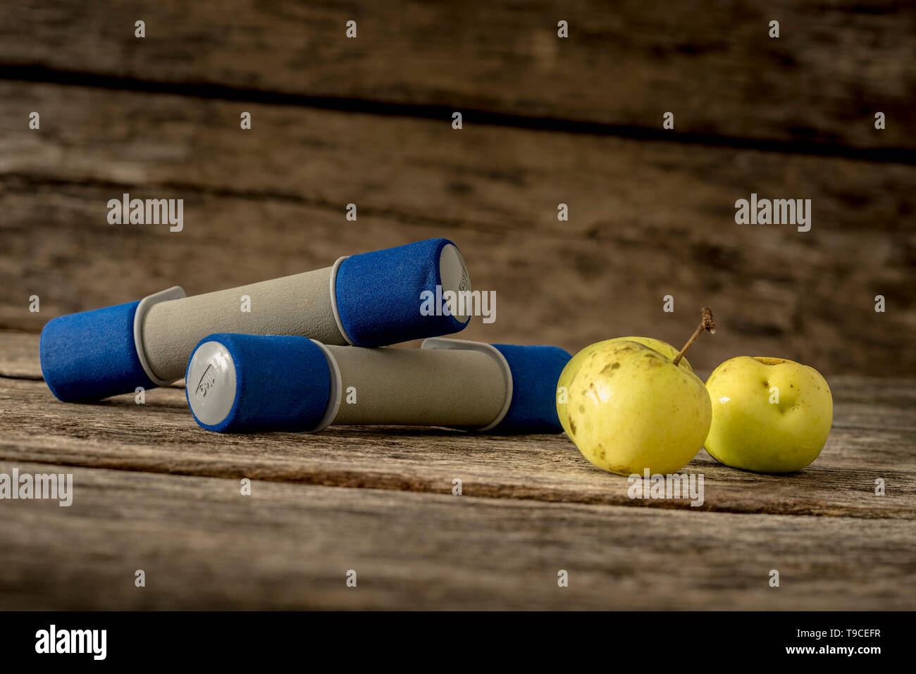 Two workout dumbbells and three fresh ripe apples lying on a textured ...