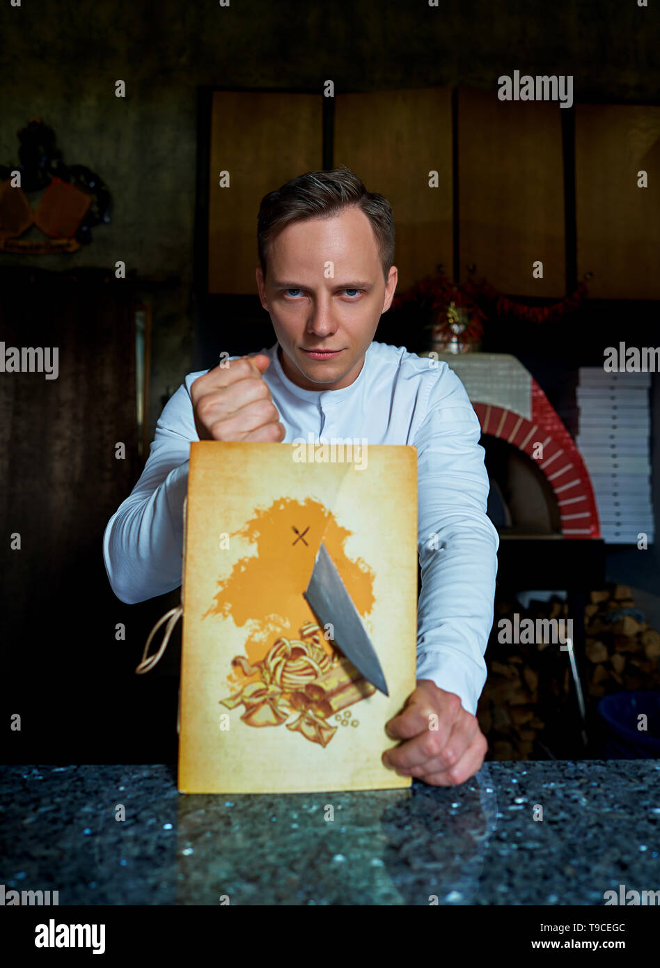 male chef cuts menu with knife Stock Photo - Alamy