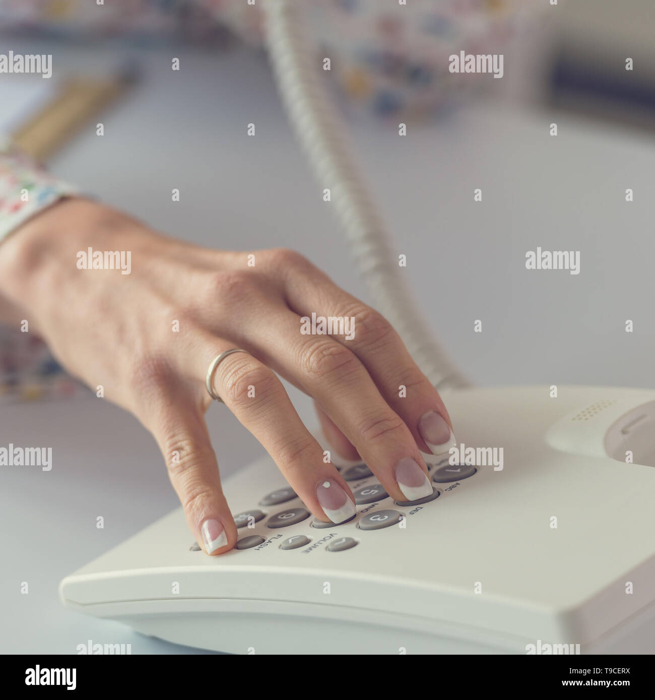 Closeup view of female hand dialing a telephone number using white ...