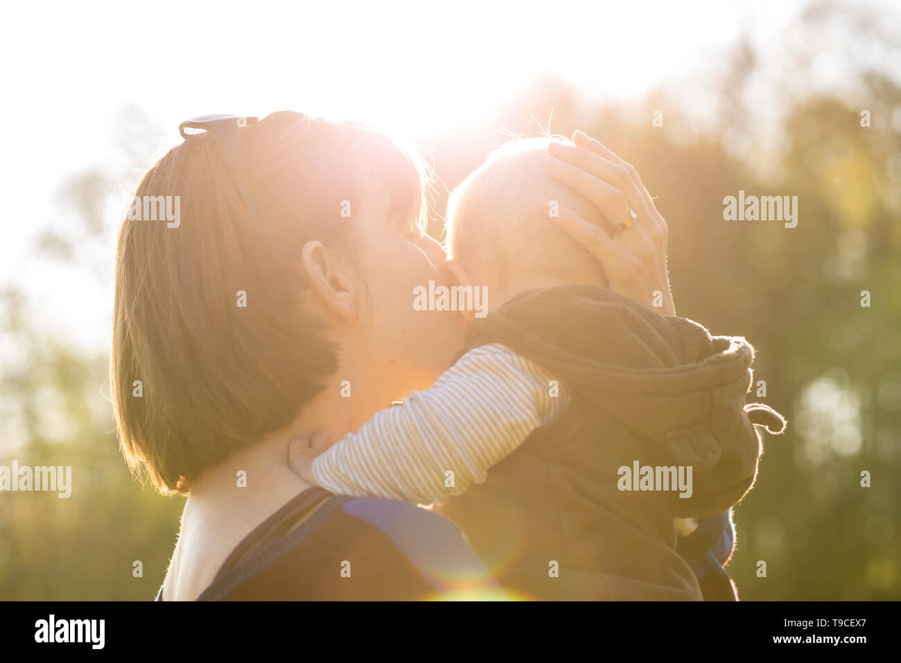Young Mother Tenderly Lifting and Kissing her Baby Boy Backlit by ...