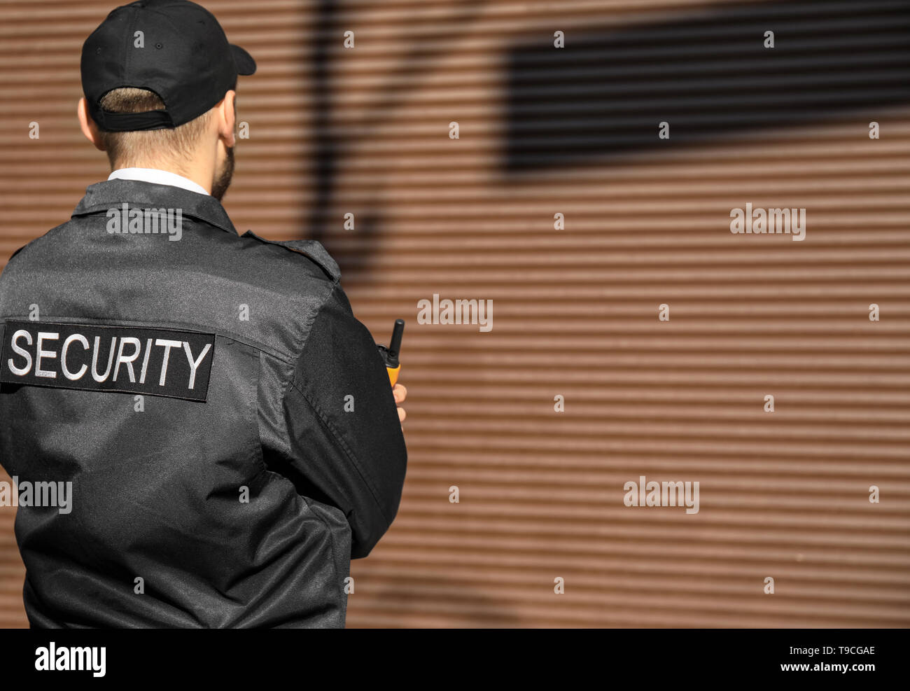 Male security guard outdoors, back view Stock Photo - Alamy
