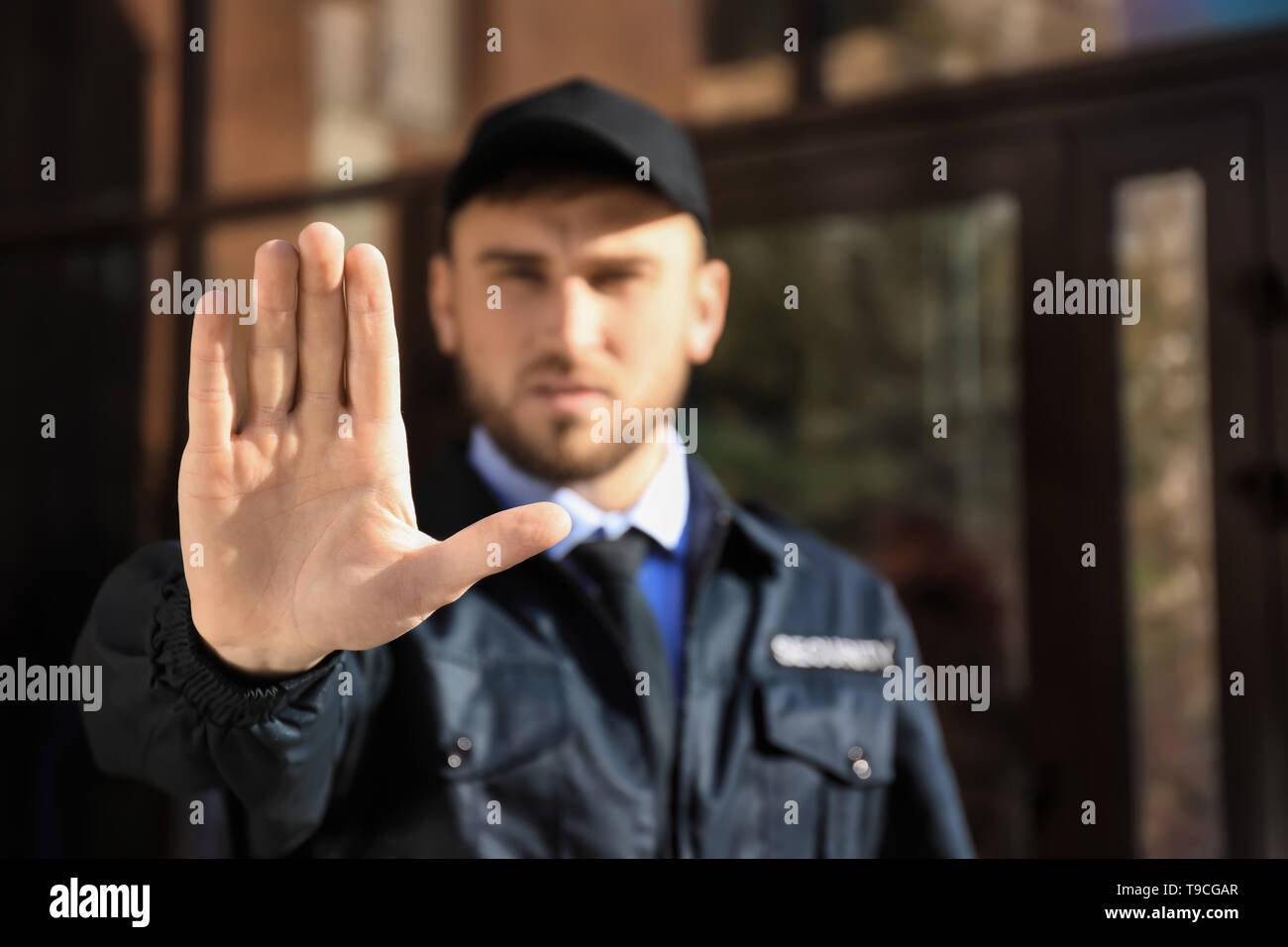 Male security guard showing Stop gesture outdoors Stock Photo - Alamy