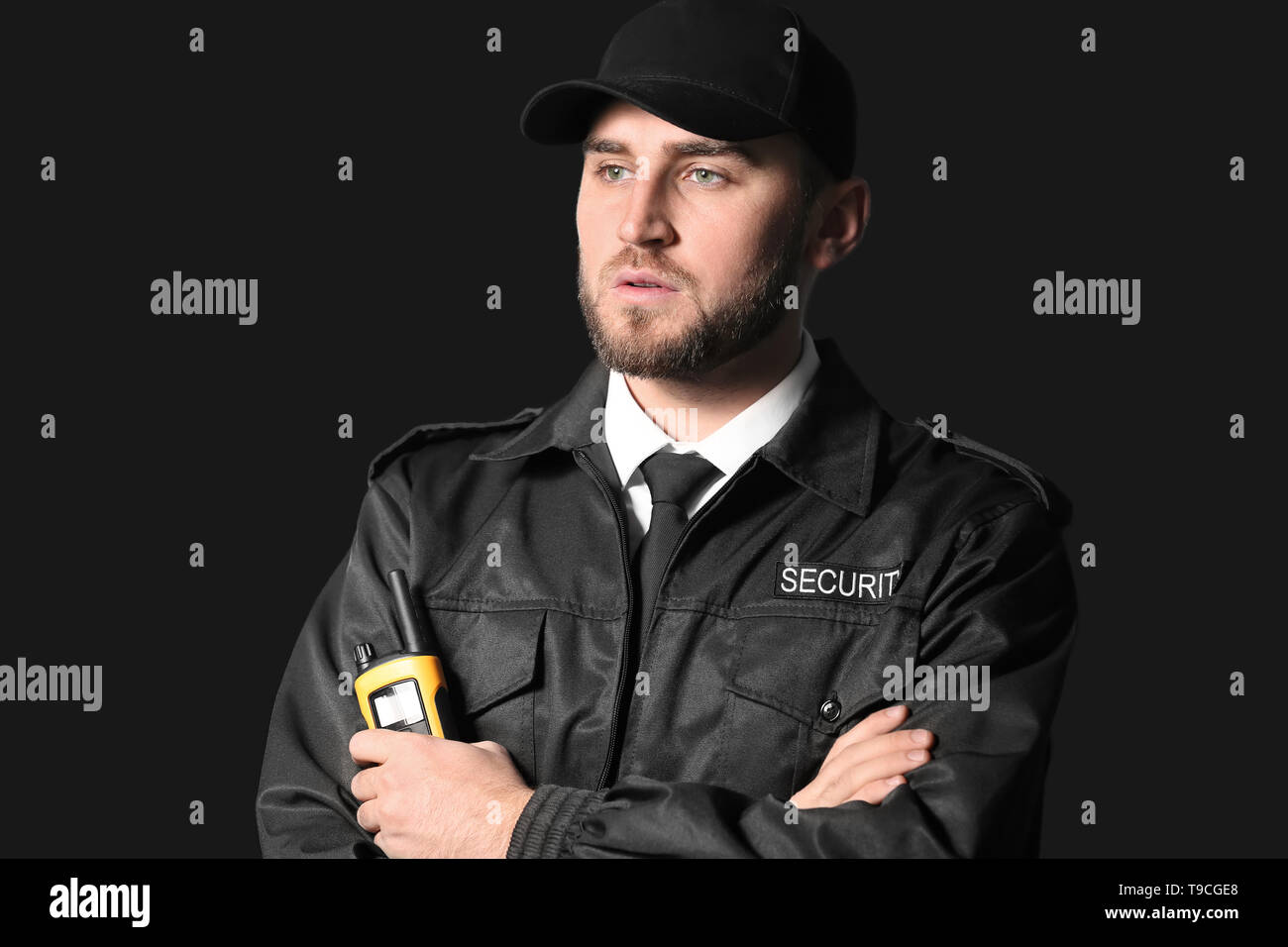Male security guard with portable radio transmitter on dark background ...