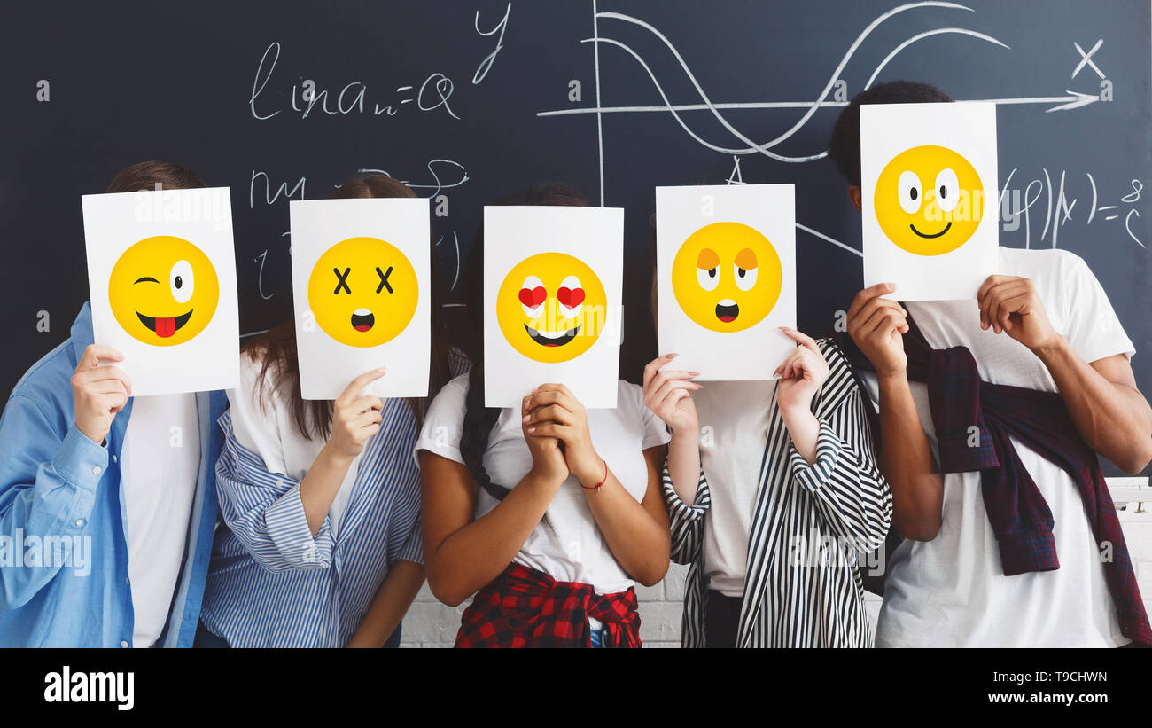 Students holding papers with emotions over chalkboard Stock Photo - Alamy