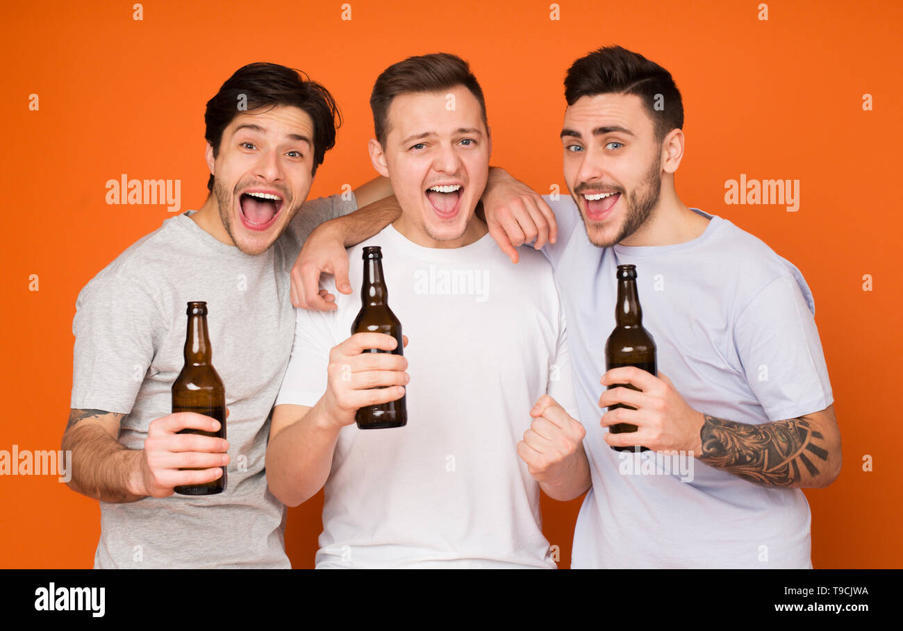 Hurray, weekend! Men Holding Beer Bottles, Orange Background Stock ...
