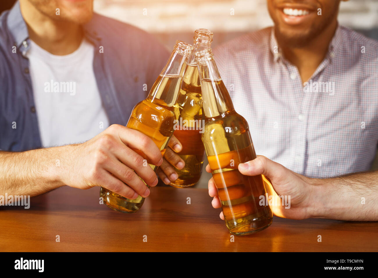 Clinking Bottles Of Beer. Men Having Rest In Pub Stock Photo - Alamy