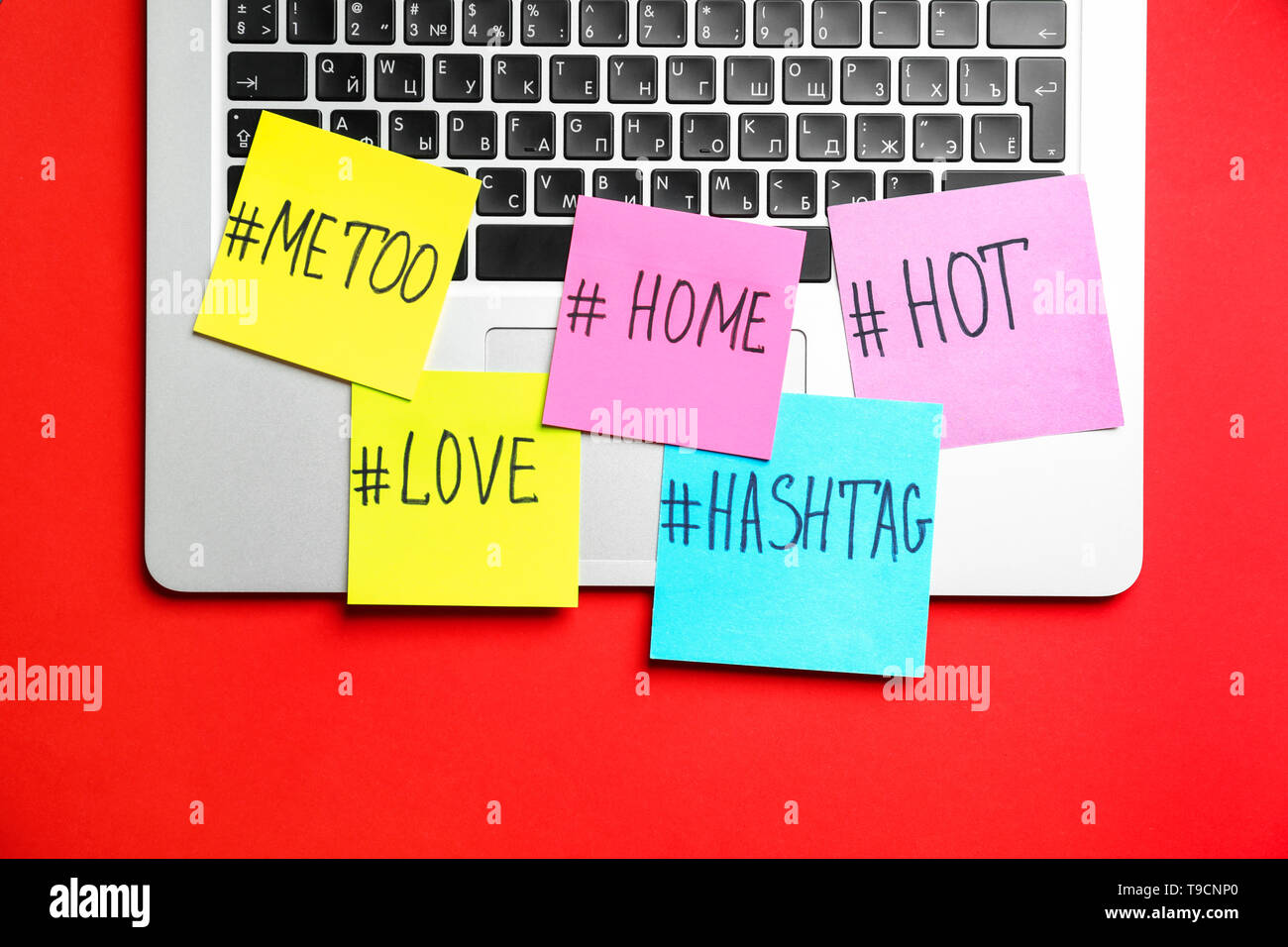 Laptop and paper sheets with popular hashtags on color background Stock ...