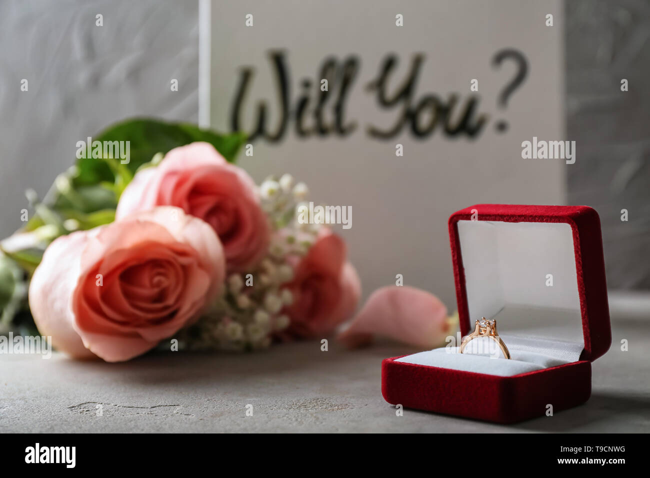Box with beautiful engagement ring and roses on grey table Stock Photo ...