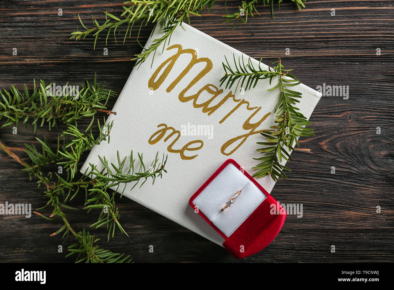 Beautiful engagement ring and paper with text MARRY ME on wooden table ...