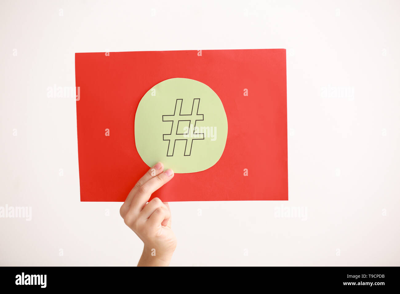 Female hand holding sheet of paper with hashtag sign on white ...