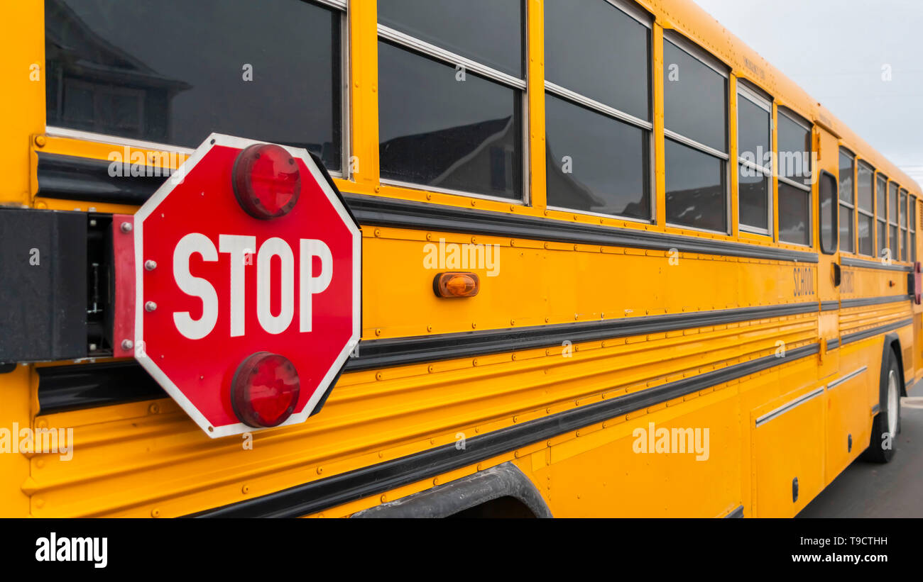 Panorama Exterior view of a yellow school bus with a red stop sign and ...