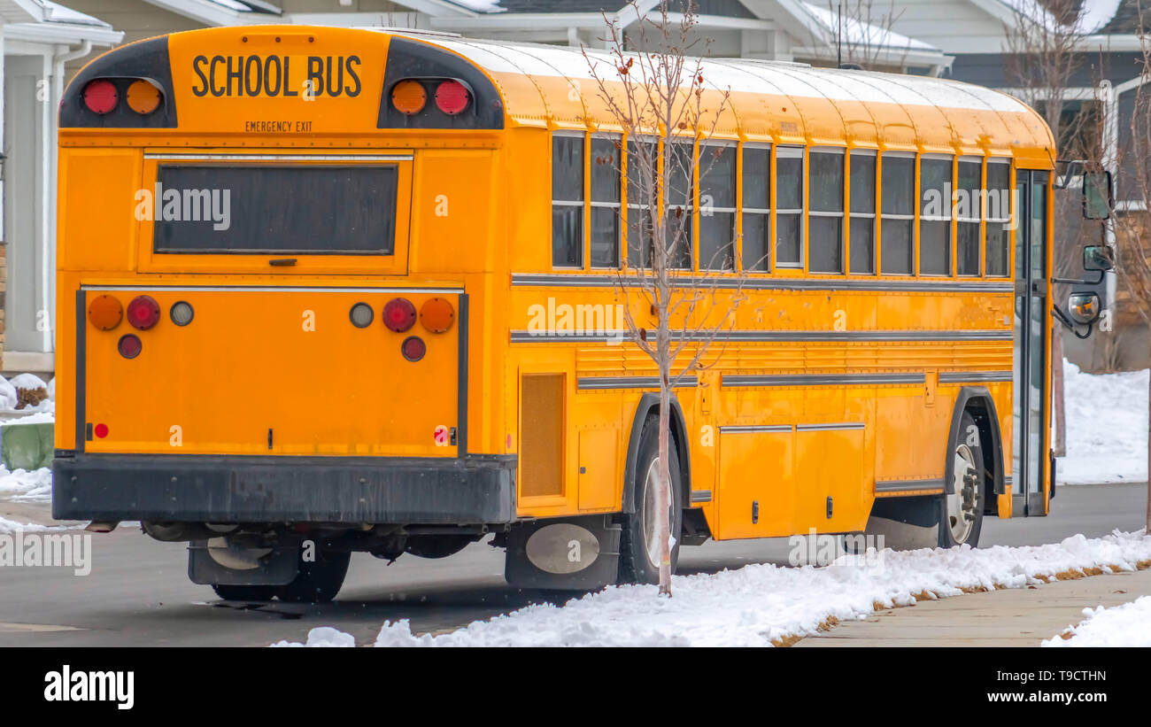 Panorama Rear view of a yellow school bus running on a road with fresh ...