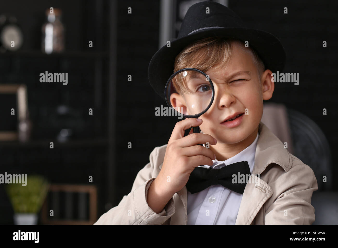 Cute little detective with magnifying glass indoors Stock Photo - Alamy
