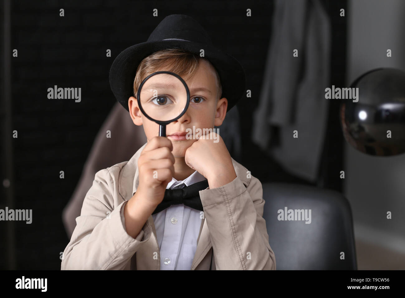 Cute little detective with magnifying glass indoors Stock Photo - Alamy