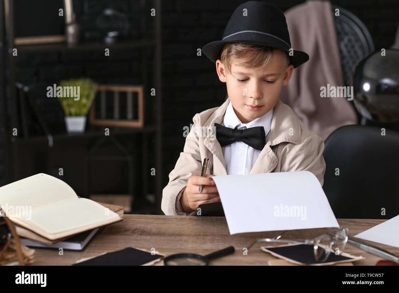 Cute little detective reading report indoors Stock Photo - Alamy