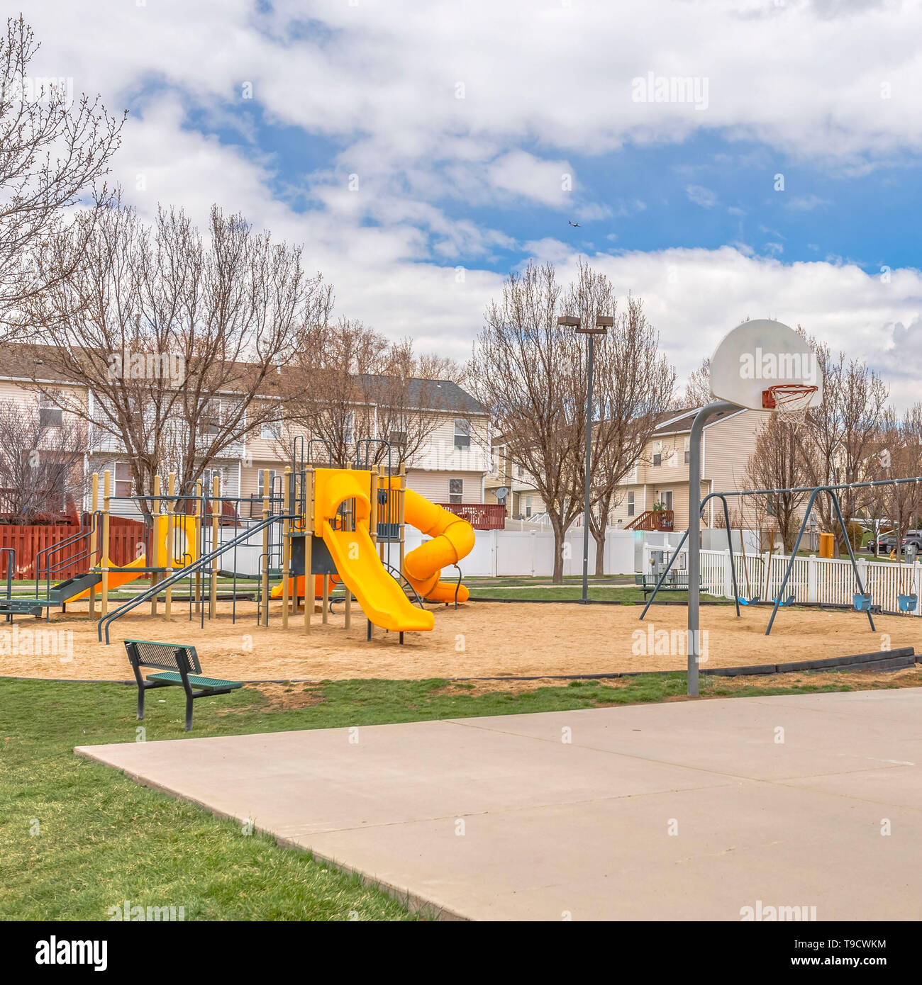 Square Playground and basketball court against homes and blue sky with ...