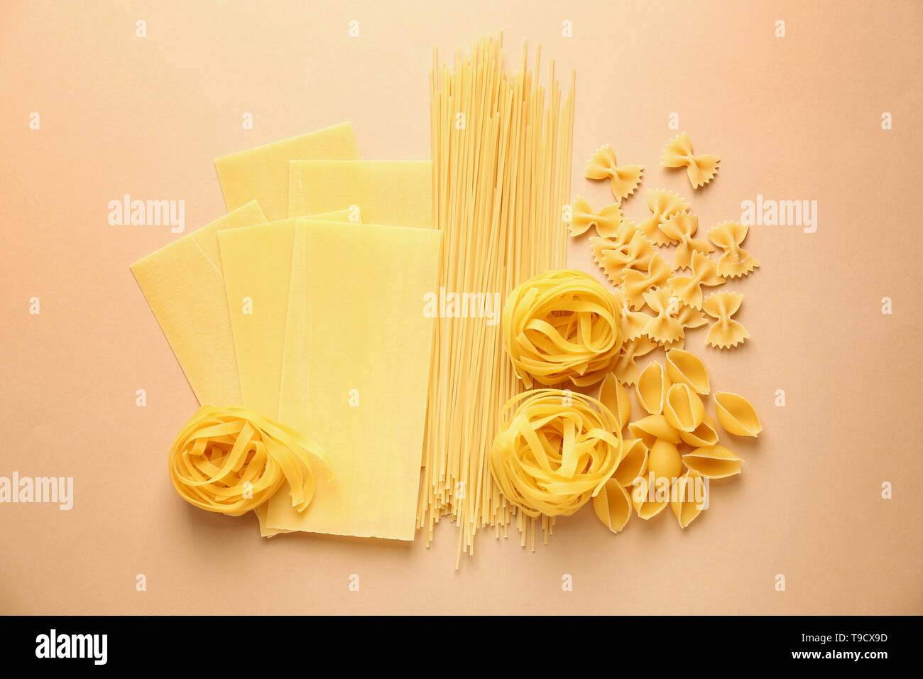 Different types of raw pasta on color background Stock Photo - Alamy