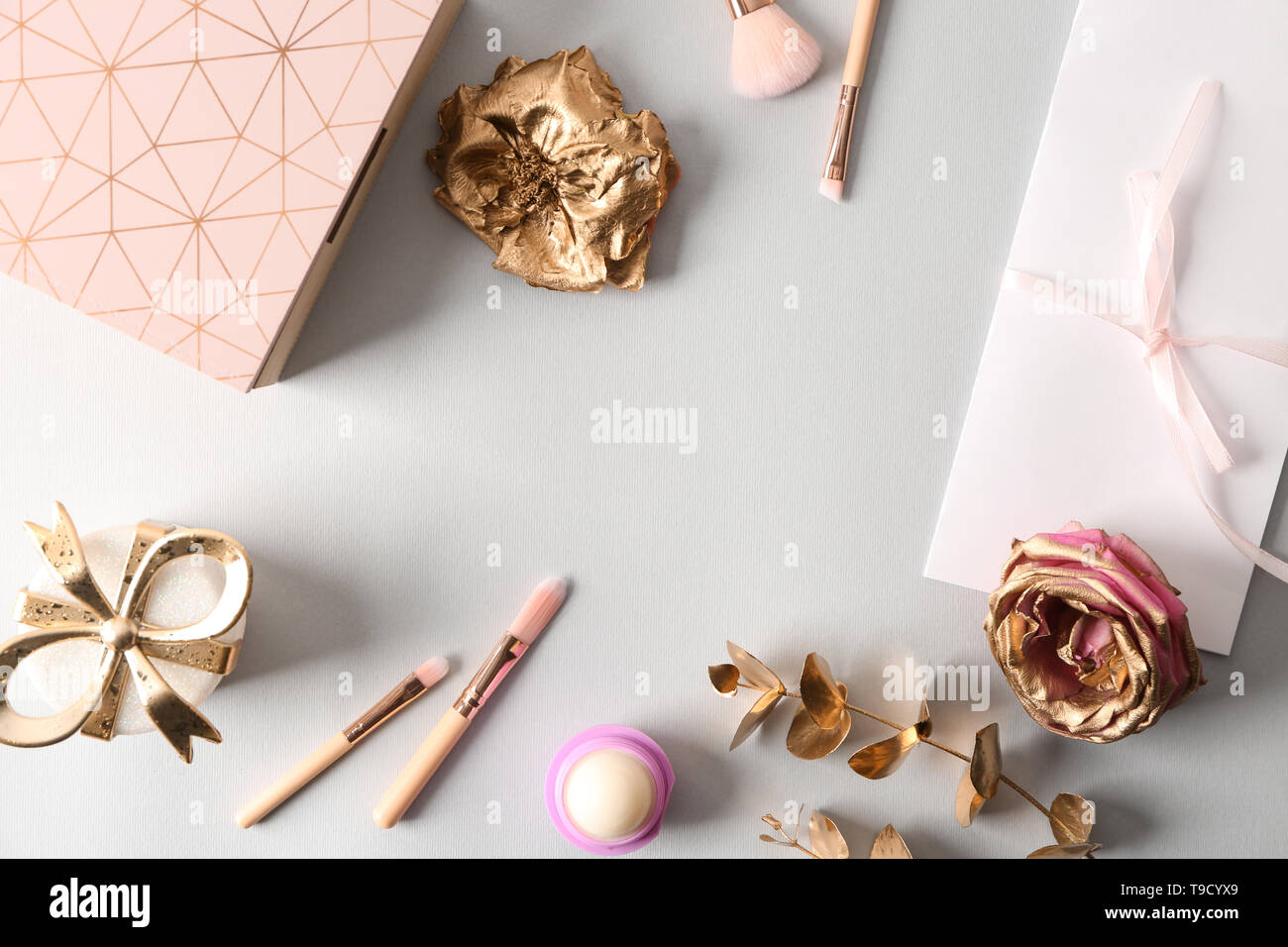 Composition with beautiful golden roses and makeup brushes on grey ...