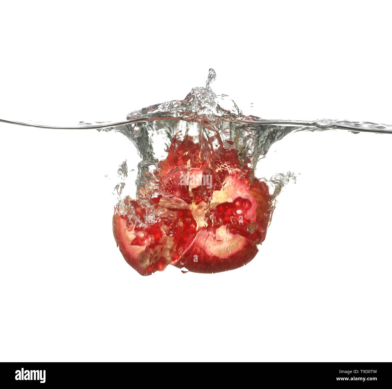 Falling of cut pomegranate into water on white background Stock Photo ...