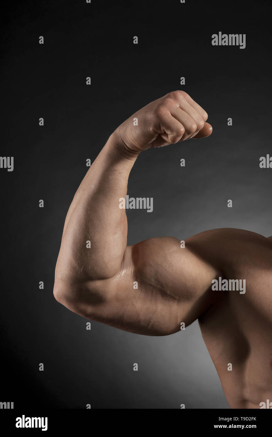 Arm of muscular bodybuilder on dark background Stock Photo - Alamy