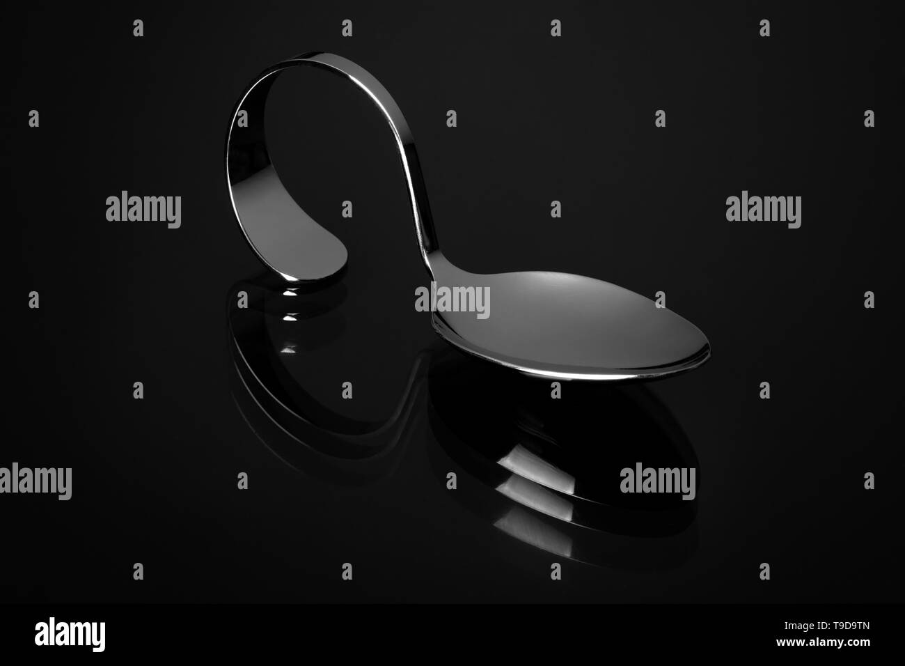curved chrome spoon snack with reflection on a dark surface Stock Photo ...