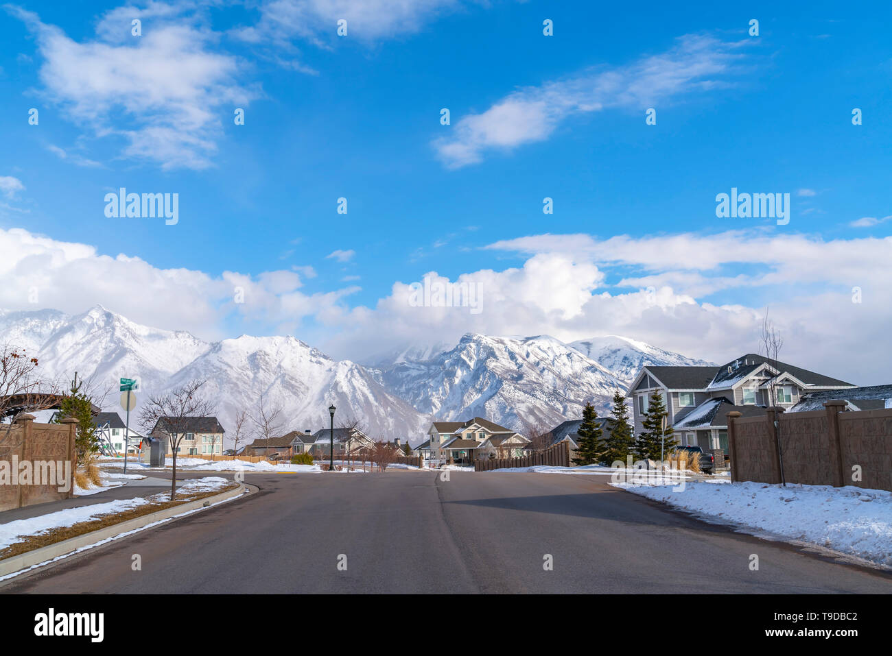 Road and homes on a snowy neighborhood viewed on a sunny winter day ...