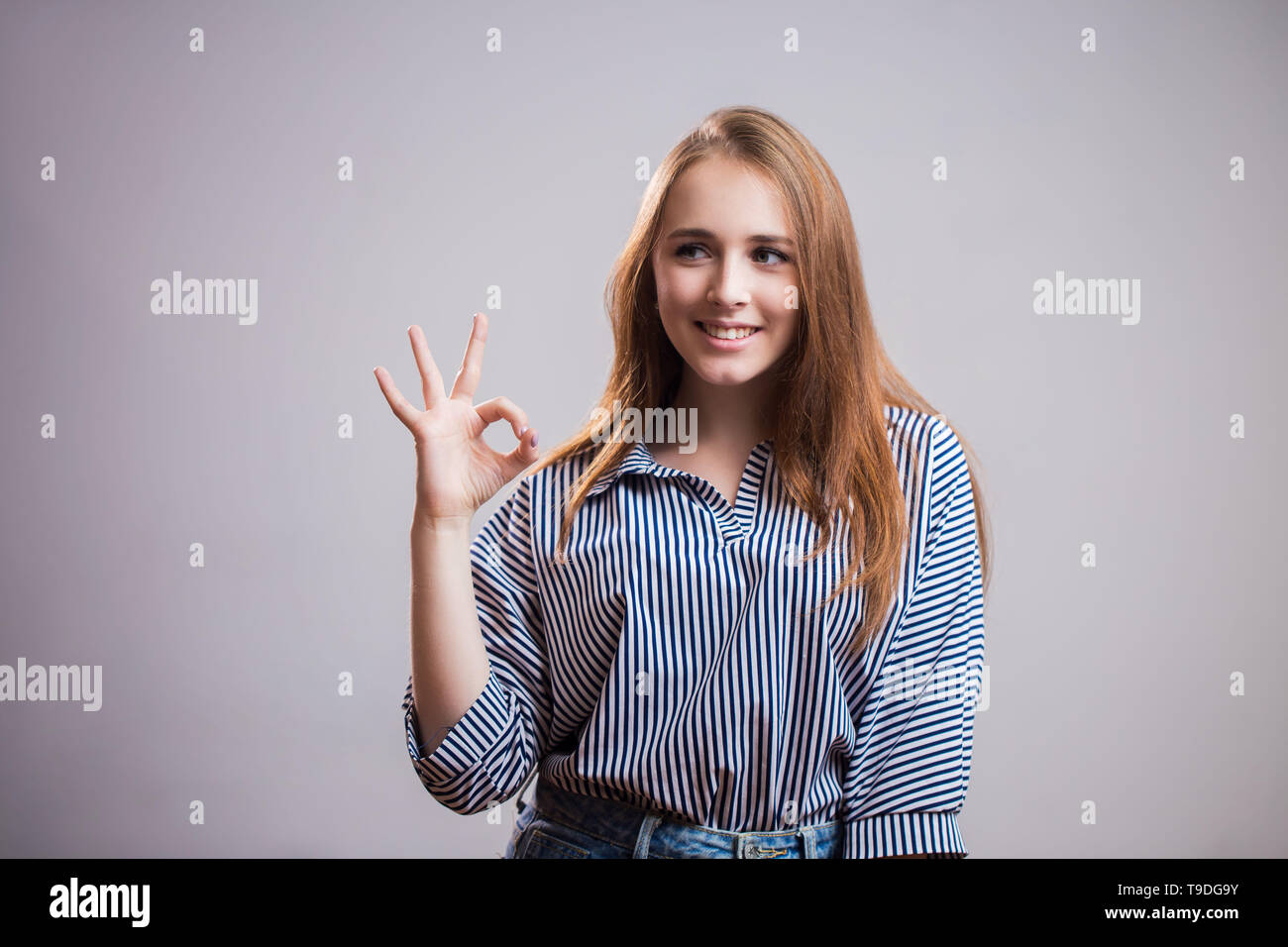 Happy young girl smiling and showing OK sign . Presenting your product ...