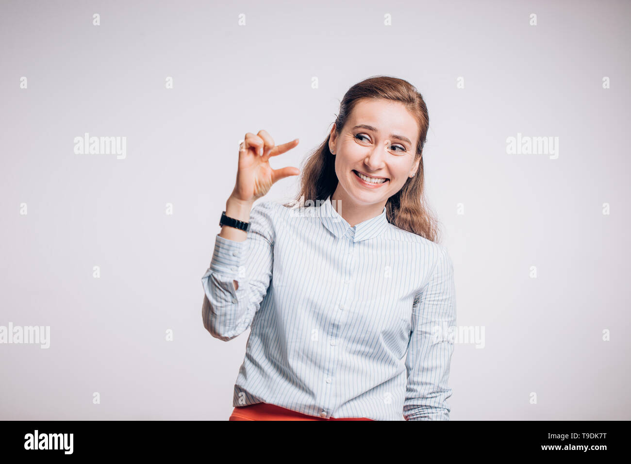 Portrait of cheerful pretty woman shows something tiny with hand, girl ...