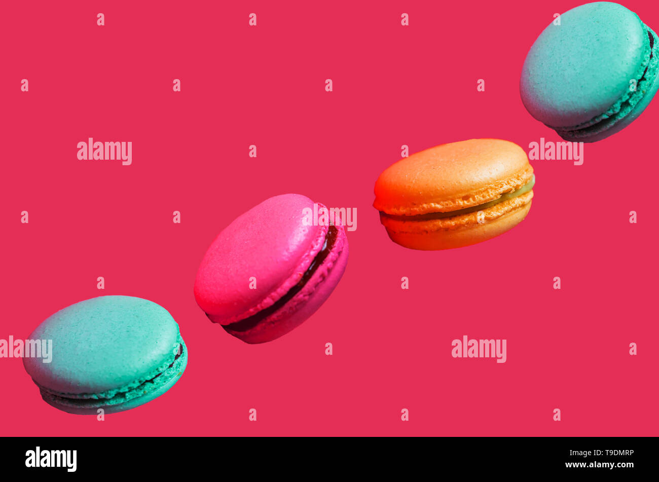 Different types of macaroons in motion falling on light pink background ...